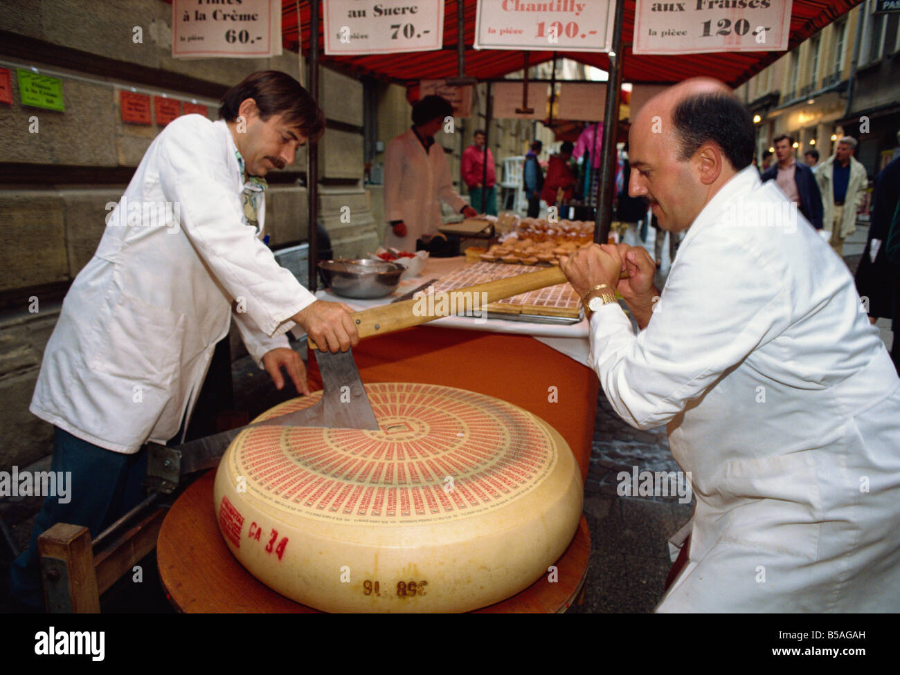 Two foot diameter Gruyere cheese being cut to size in market ...