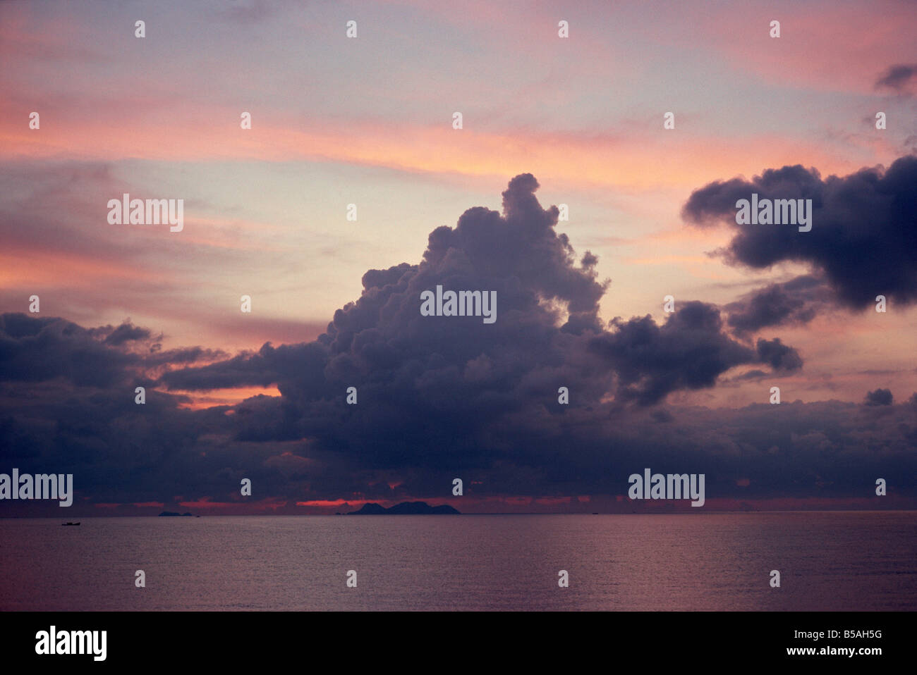 Towering dark grey clouds in a pink and blue sky over the sea in ...