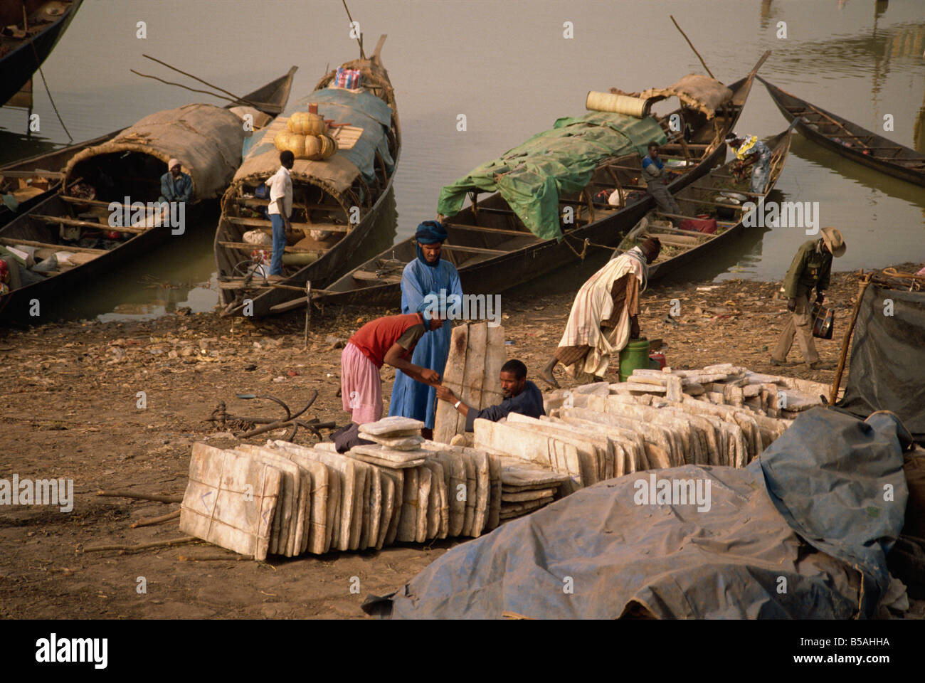 Blocks of salt on river bank with pirogues in background Mopti Mali ...