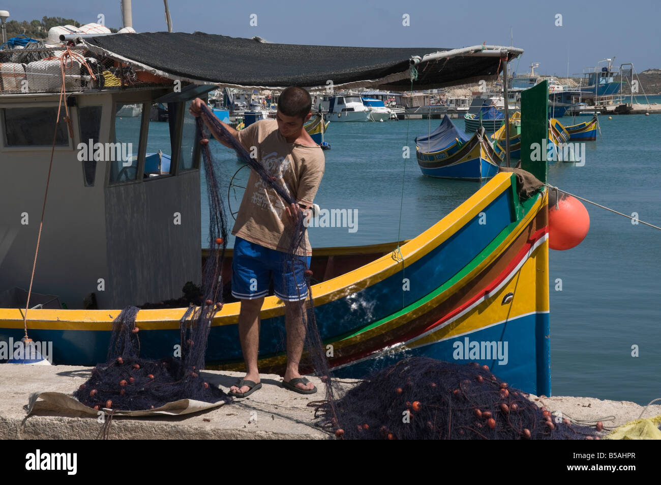 Sorting out the fishing net with brightly coloured fishing boats called ...