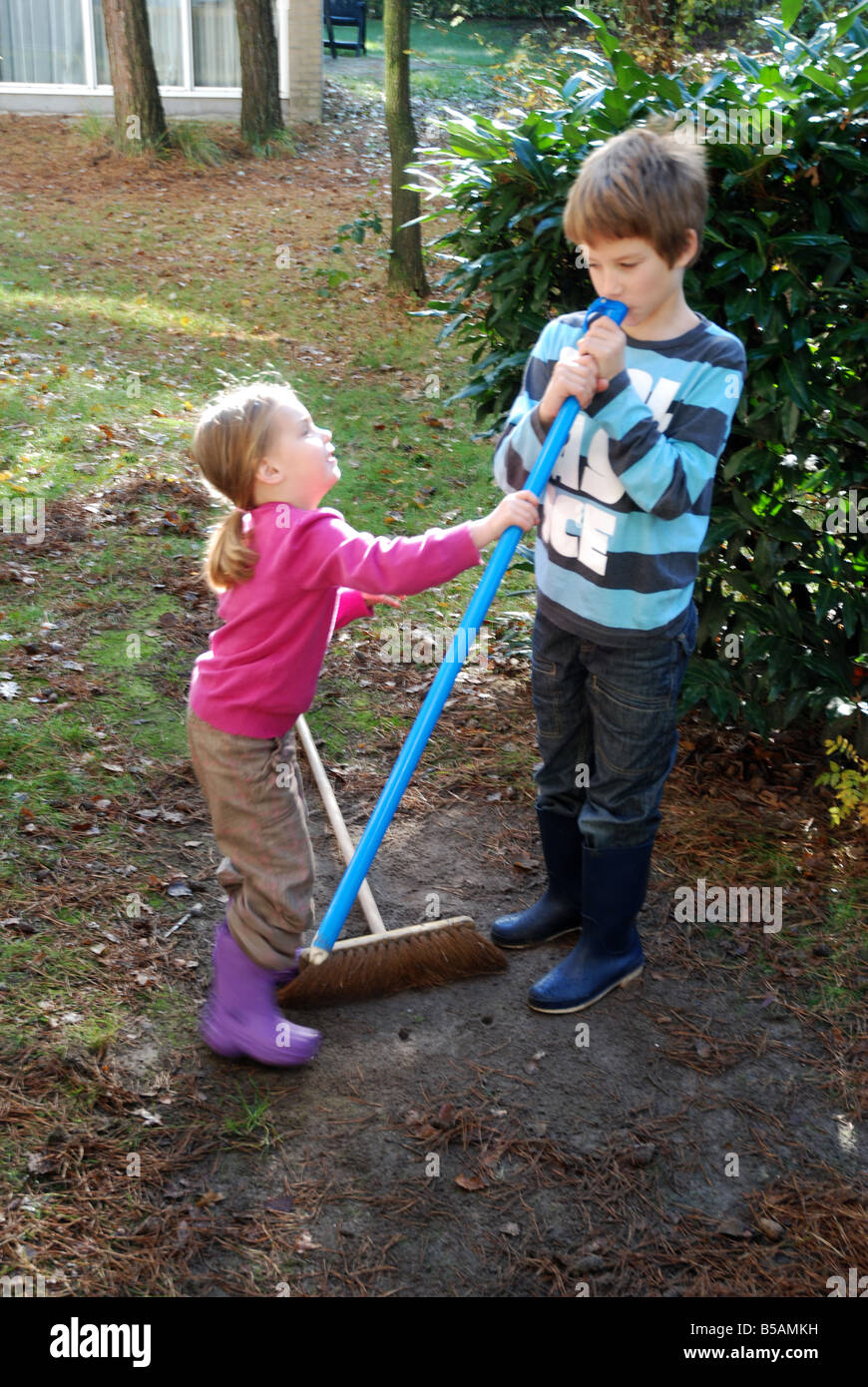two children playing in garden with broom and stick Stock Photo - Alamy