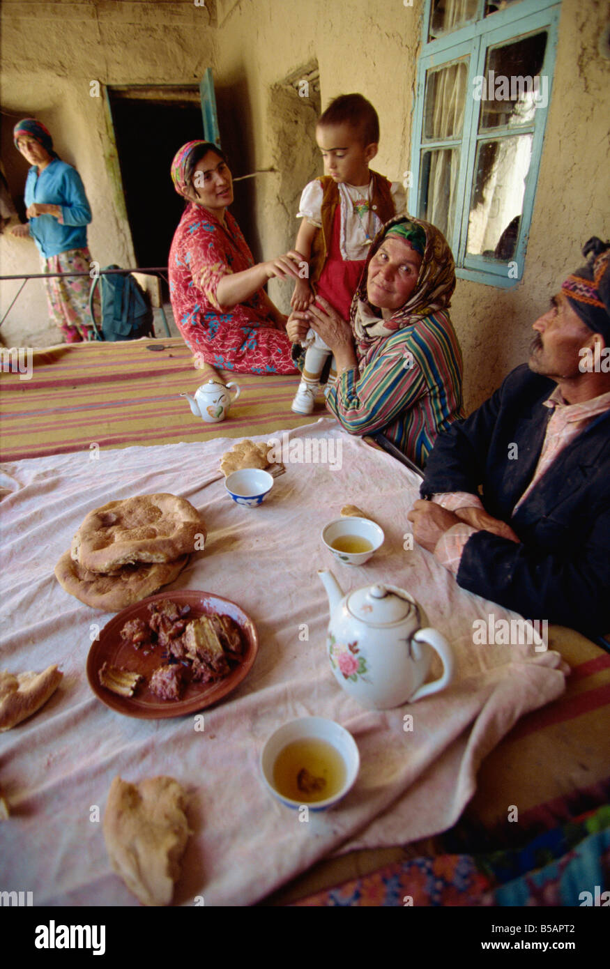 Tajik family at table with typical offering of mutton tea and bread ...