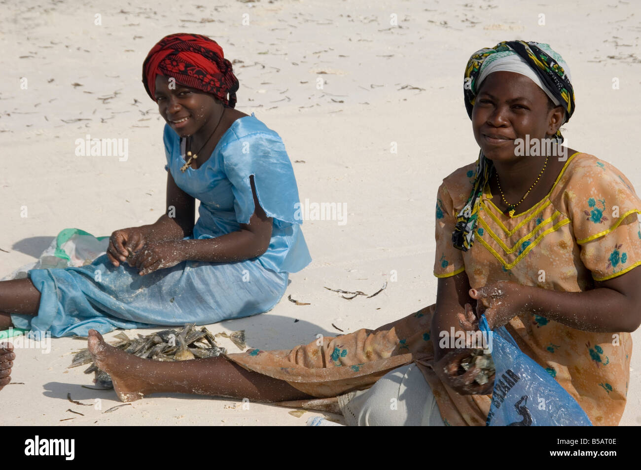 Local women in colourful dress sorting clams on the beach Paje Zanzibar ...