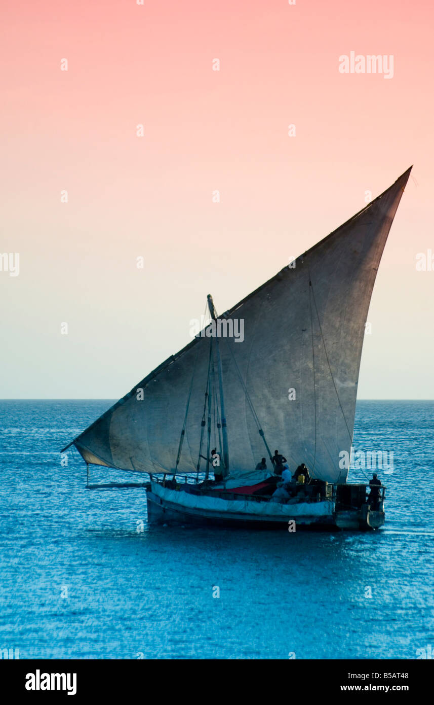 A traditional wooden dhow sailing near Stone Town at sunset Zanzibar ...