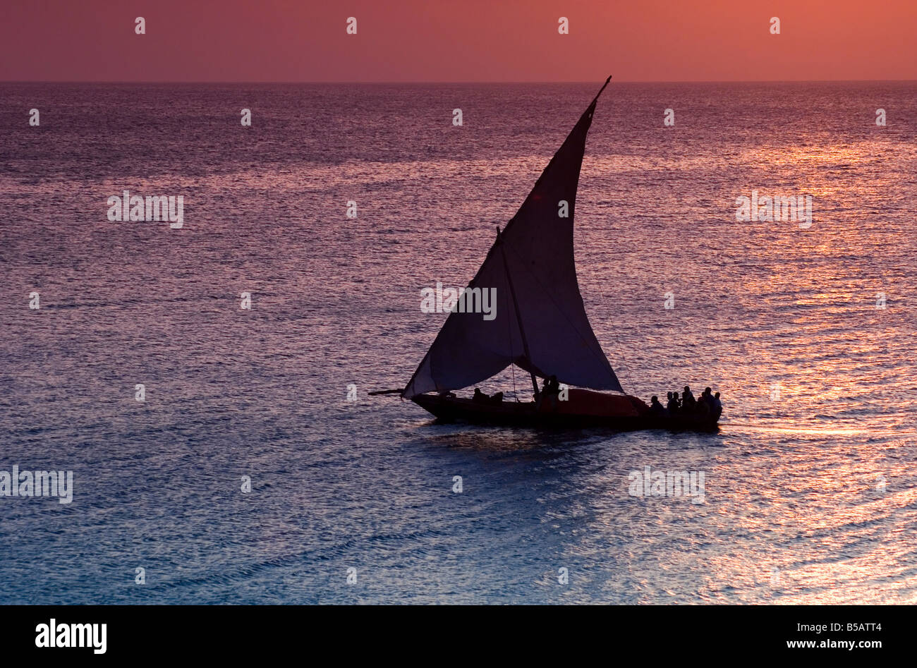A dhow sailing at sunset near Stone Town Zanzibar Tanzania East Africa ...