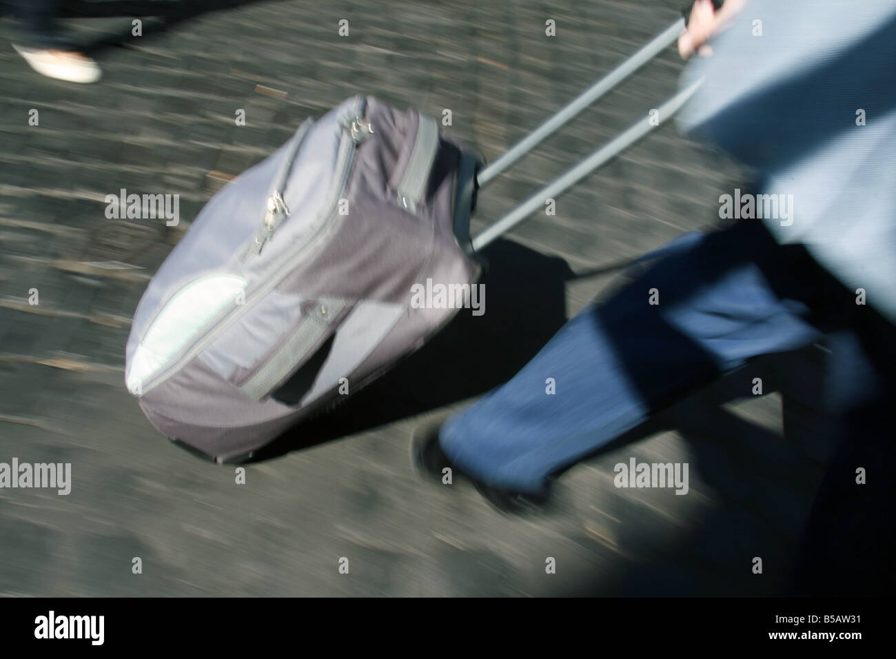 young person pulling trolley luggage case in town Stock Photo - Alamy