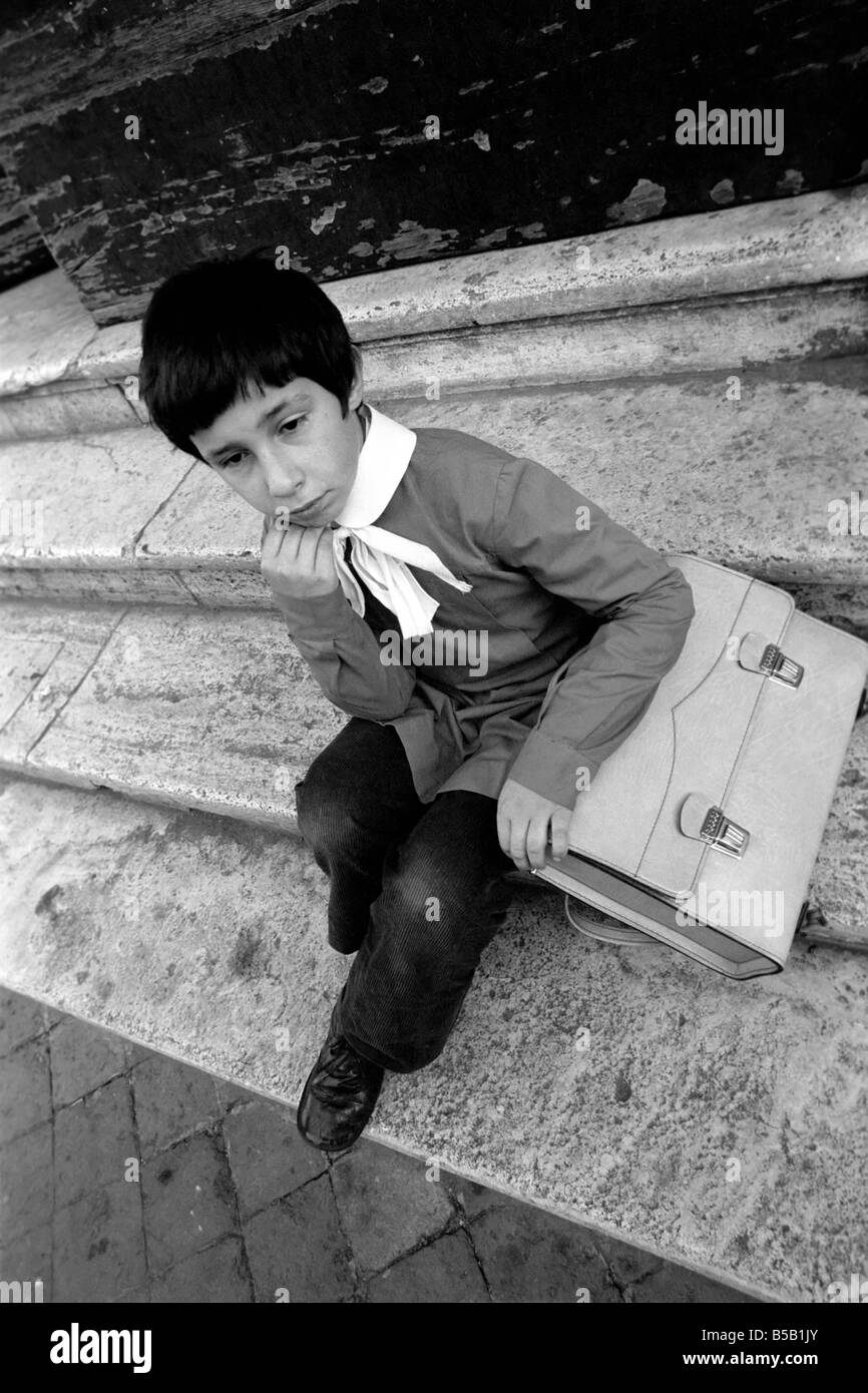 Young child sitting on the steps of his school in a poor suburb on the ...