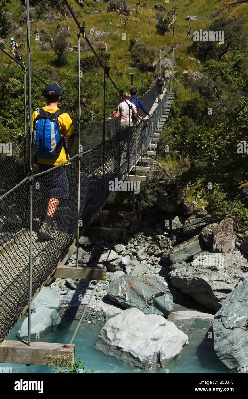 Hikers crossing a suspension bridge on Rob Roy Glacier Hiking Track ...