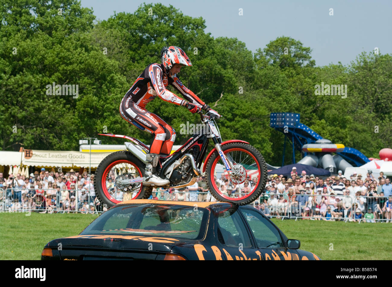 Motorcycle Stunt Rider performing on his Motorcycle Riding Over a Car ...