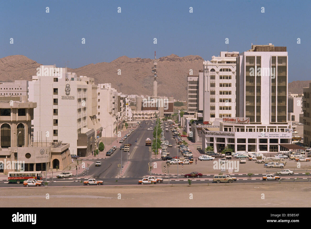 Street with modern buildings and telecommunications tower in Ruwi Oman ...