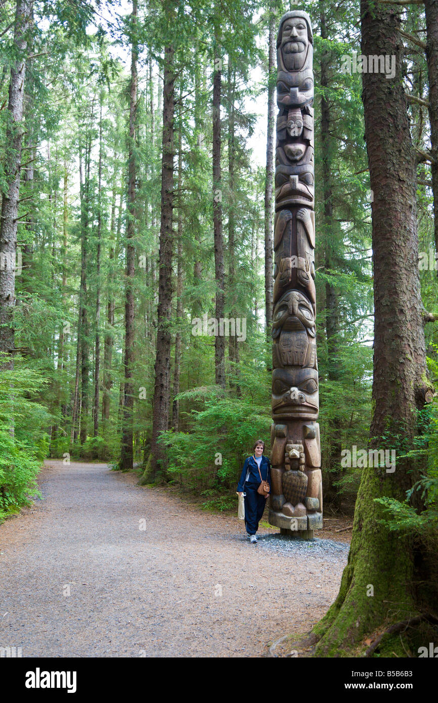 Woman standing beside totem pole in National Historical Park in Sitka ...