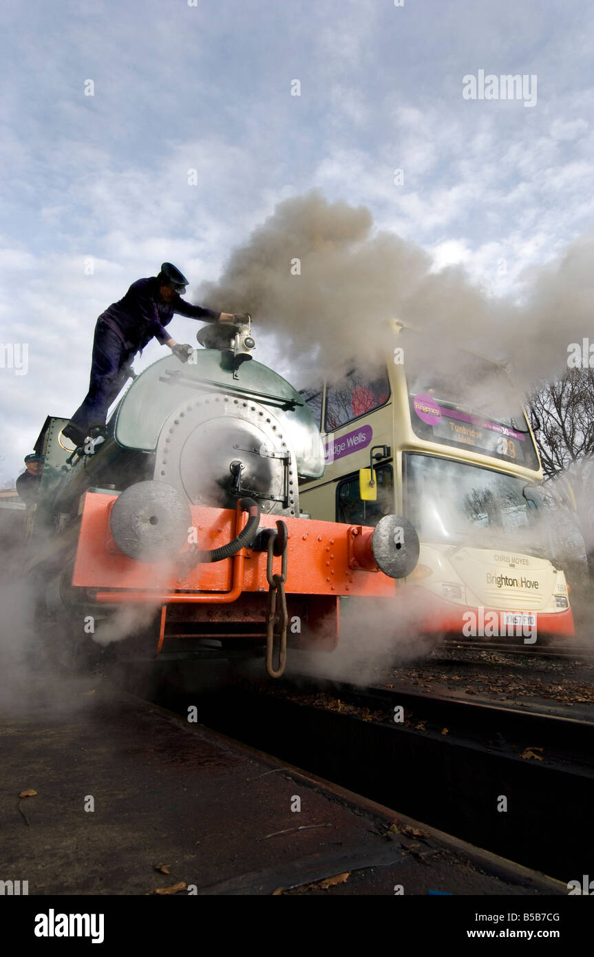 A saddletank steam locomotive with driver and fireman next to a double ...