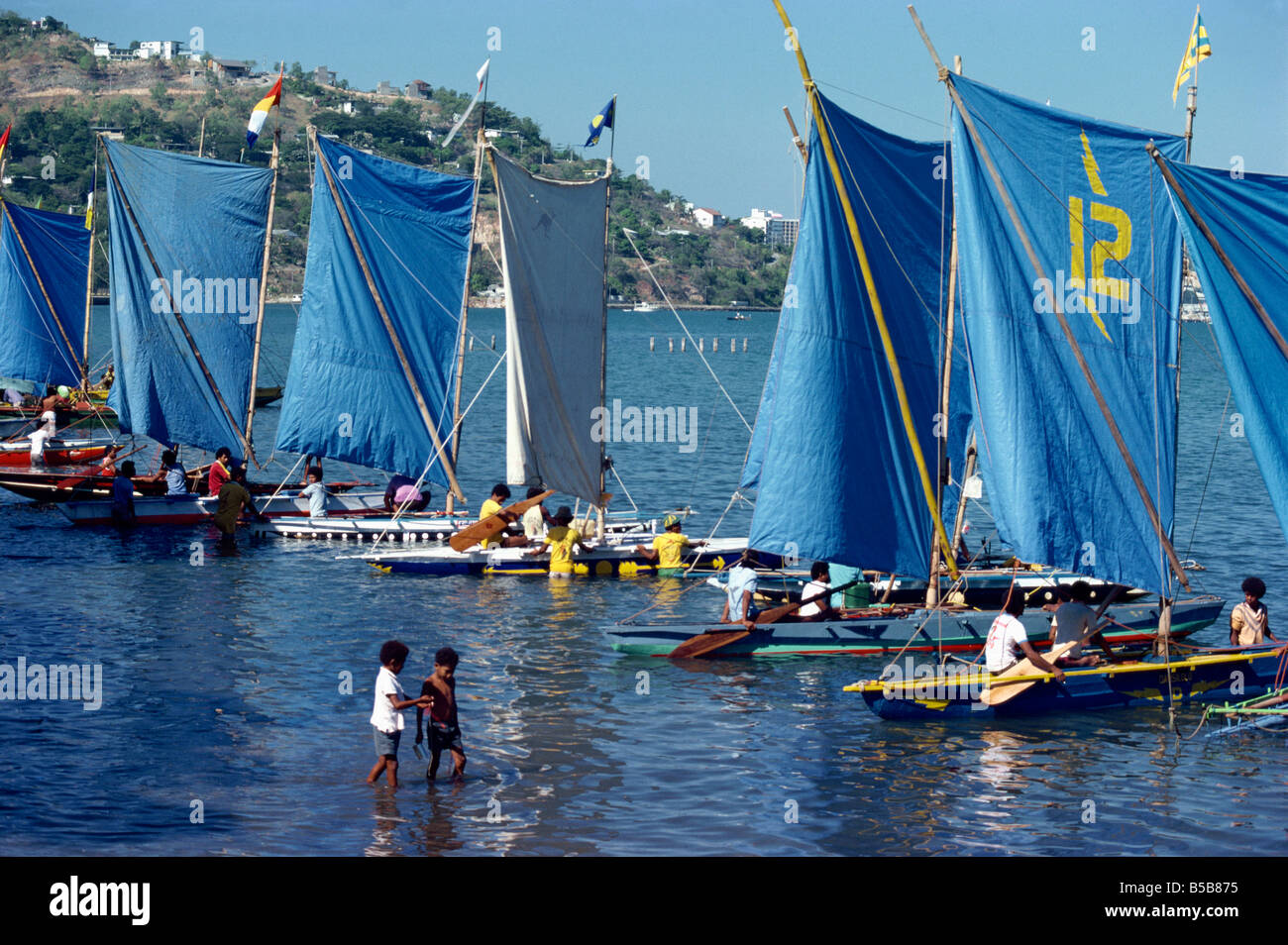 Boats with blue sails line up at the start of a Lakatoi canoe race ...
