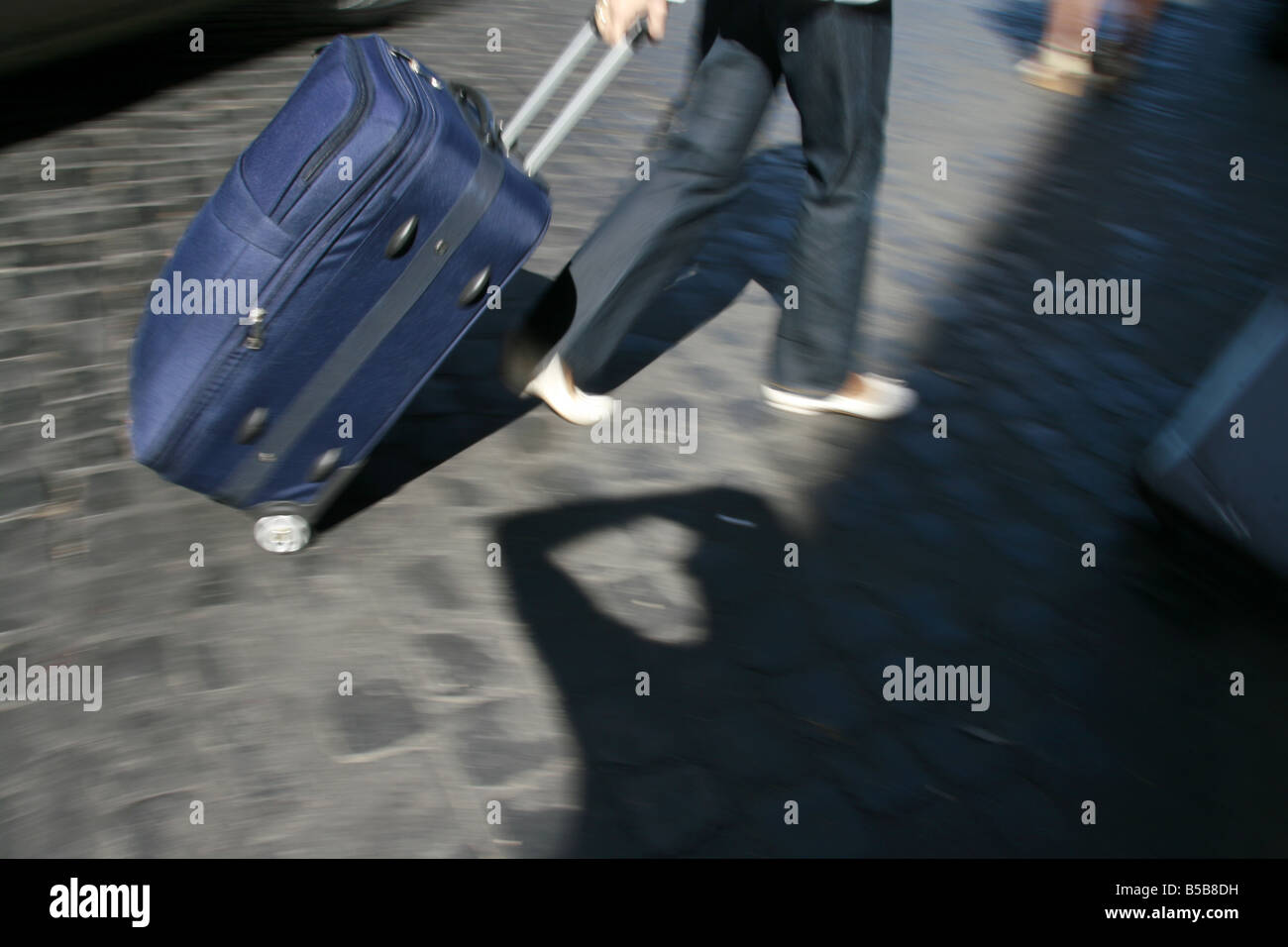 young person pulling trolley luggage case in town Stock Photo - Alamy