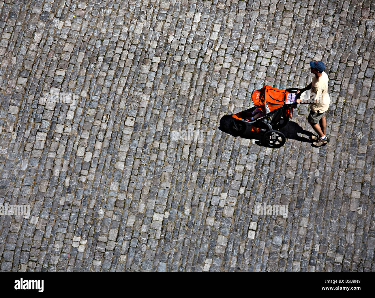 Man pushing pram across cobblestones viewed from above Rothenburg ...