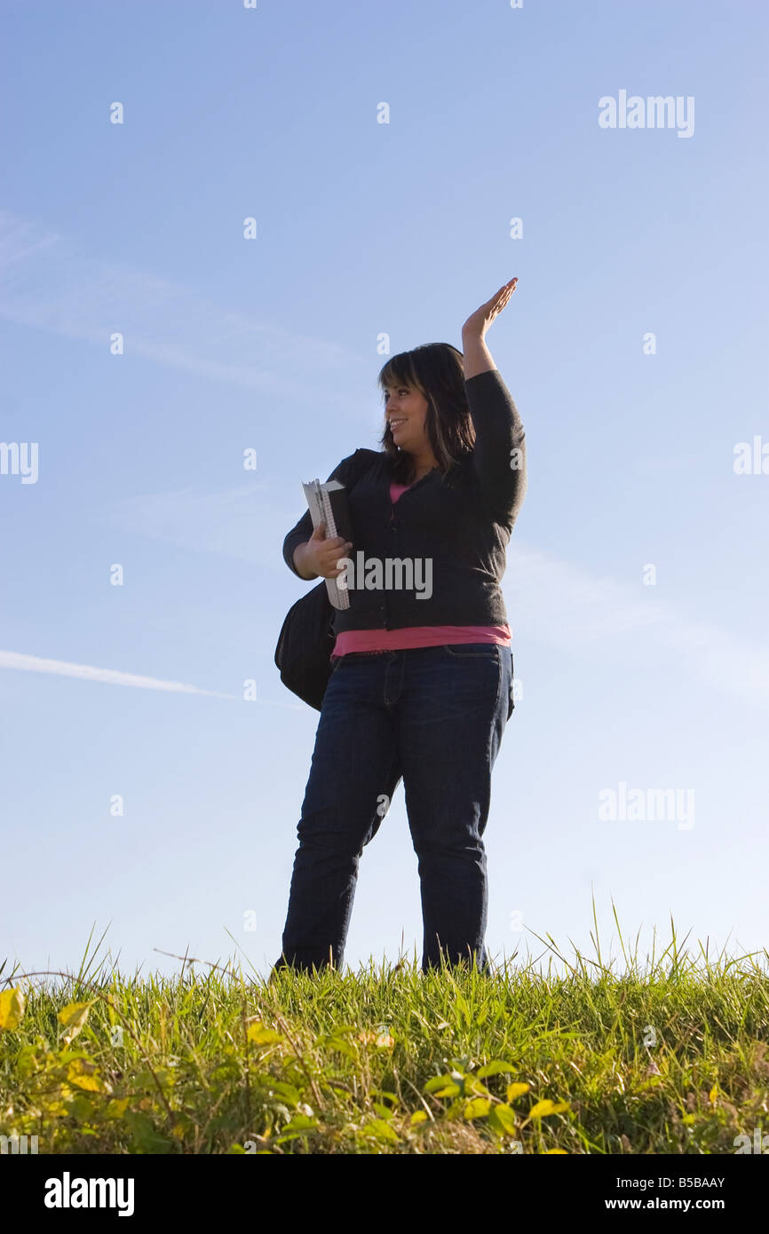 A young woman waves to her friends while walking on campus Stock Photo ...