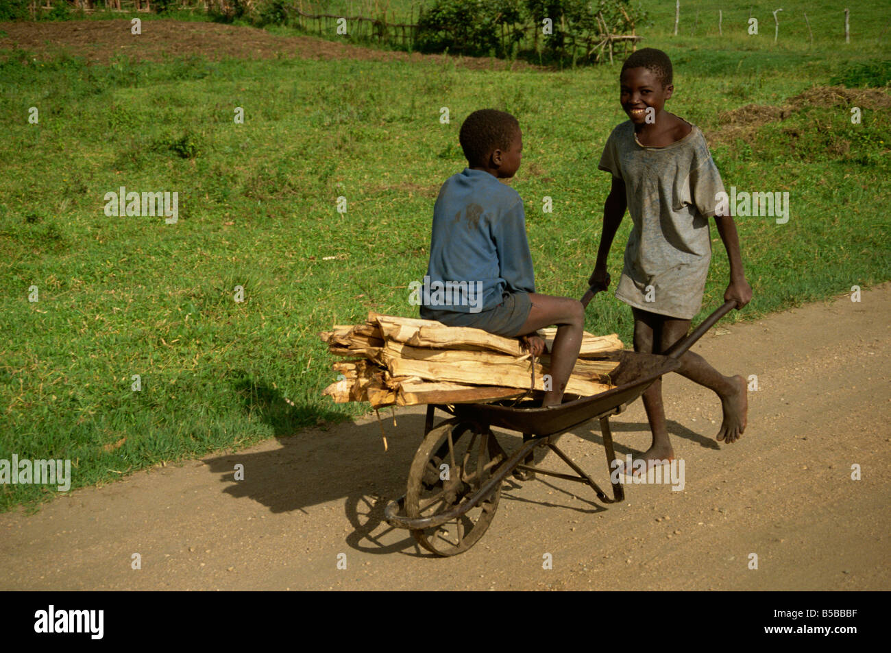 Boy pushing wheelbarrow with wood and child riding on it Fort Portal ...