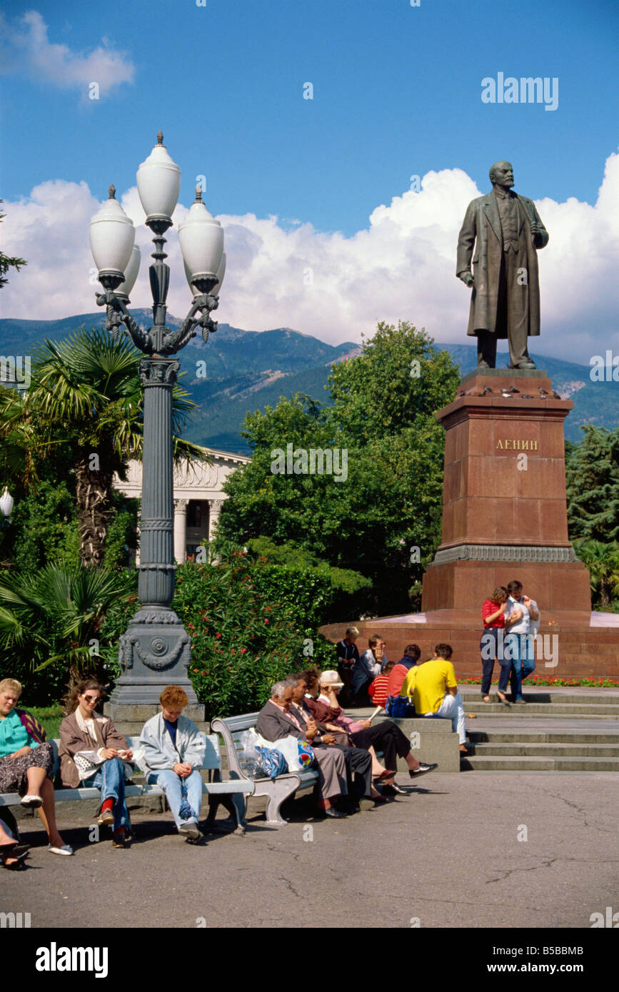 People sitting on benches near a statue of Lenin in Yalta the Crimea ...