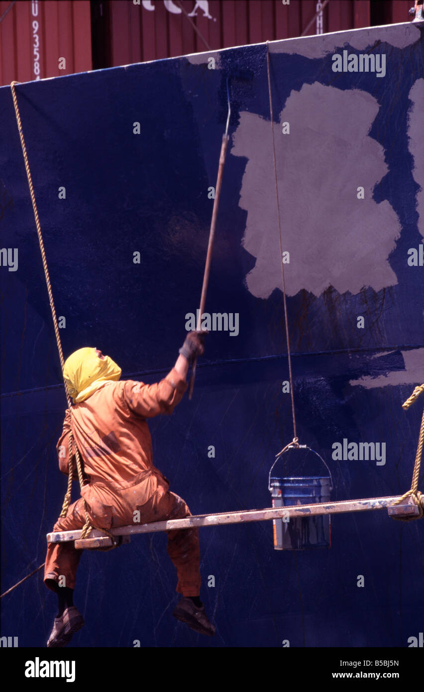 Sailor painting side of ship at quayside Stock Photo - Alamy