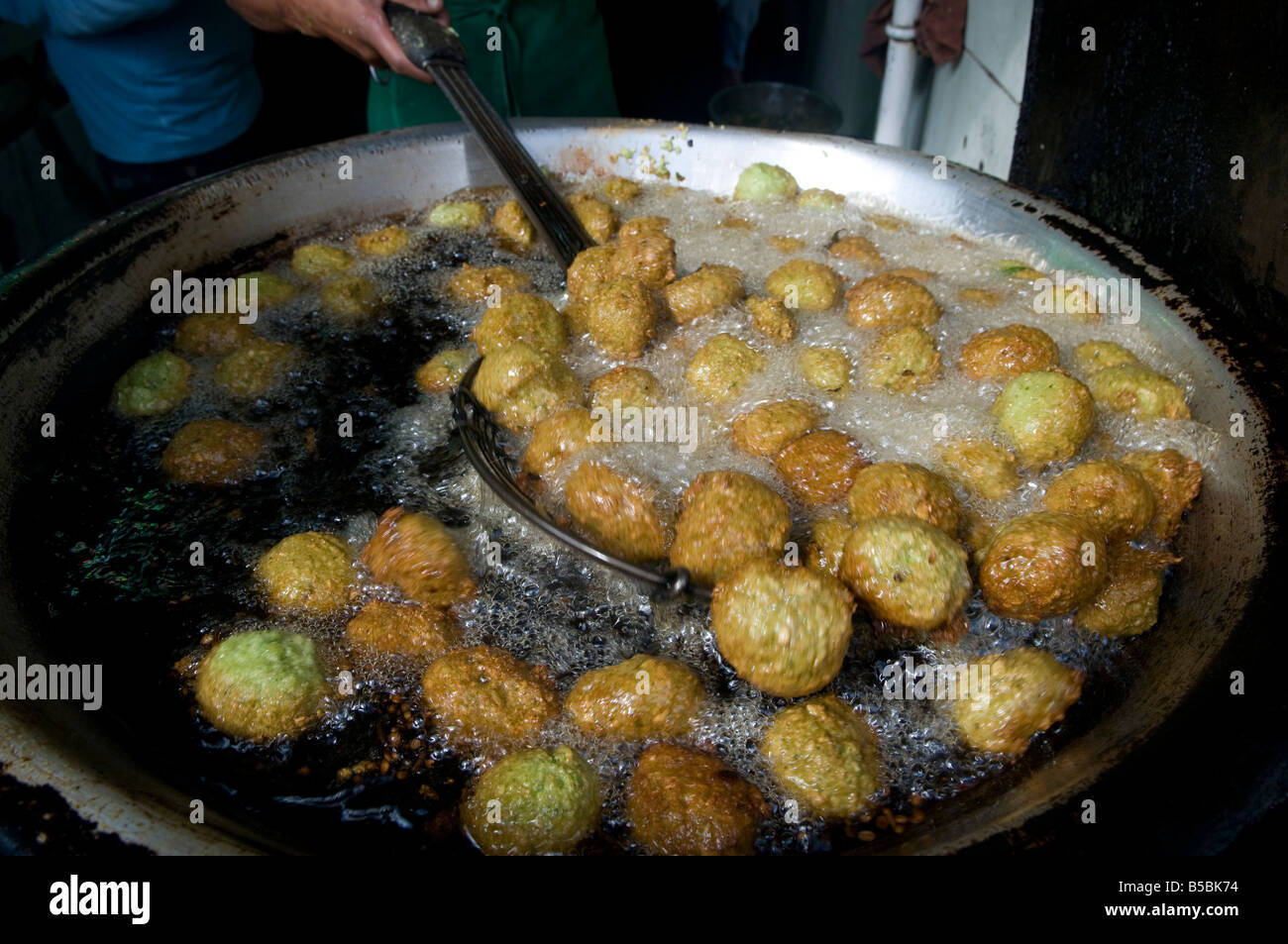 Taamiya or Falafel balls being fried in a large bowl of boiling oil at ...