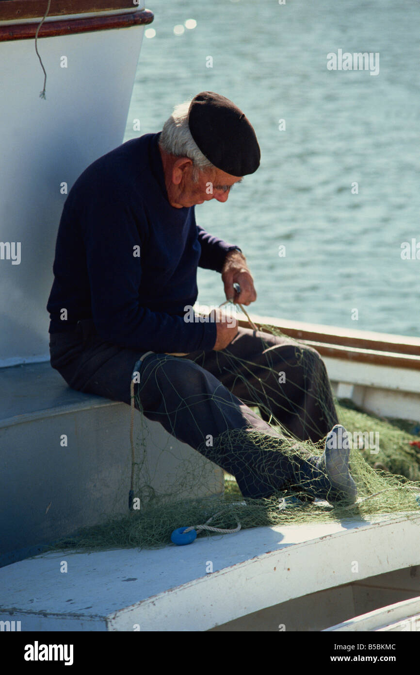 A fisherman mending his fishing nets on the Costa Brava Catalunya Spain ...