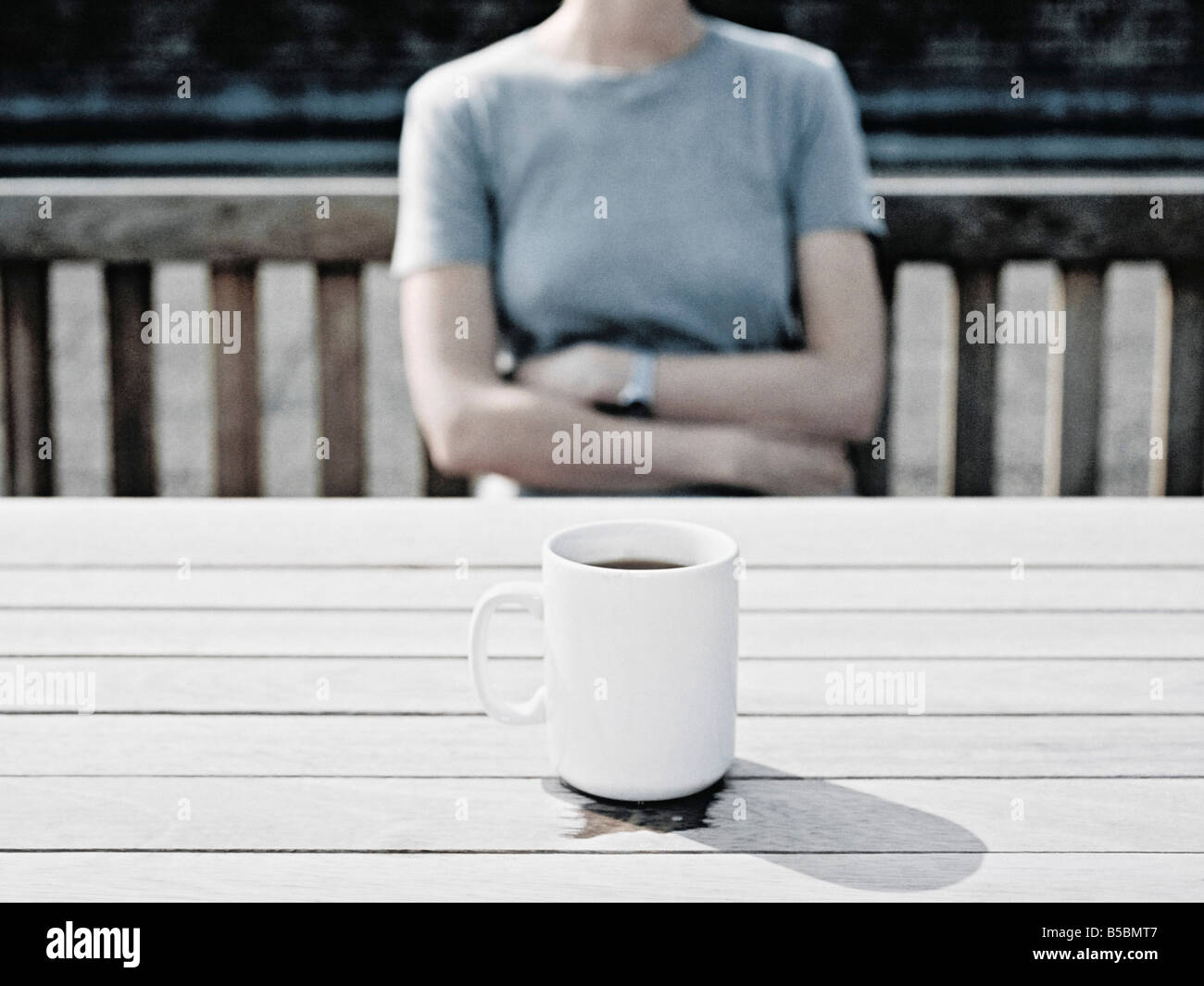 Young Woman Sitting On Bench With Arms Crossed Stock Photo - Alamy