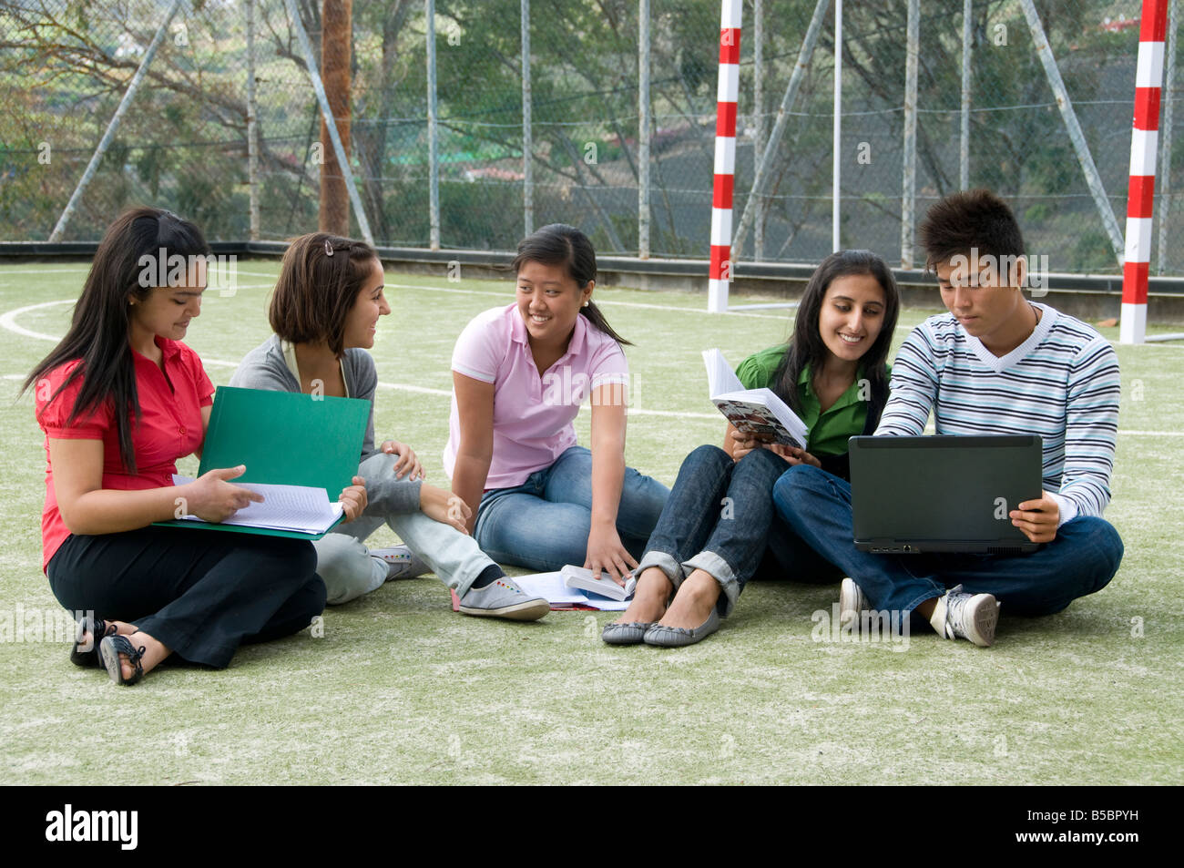 Group of senior teenage school students relax and talk together in an ...