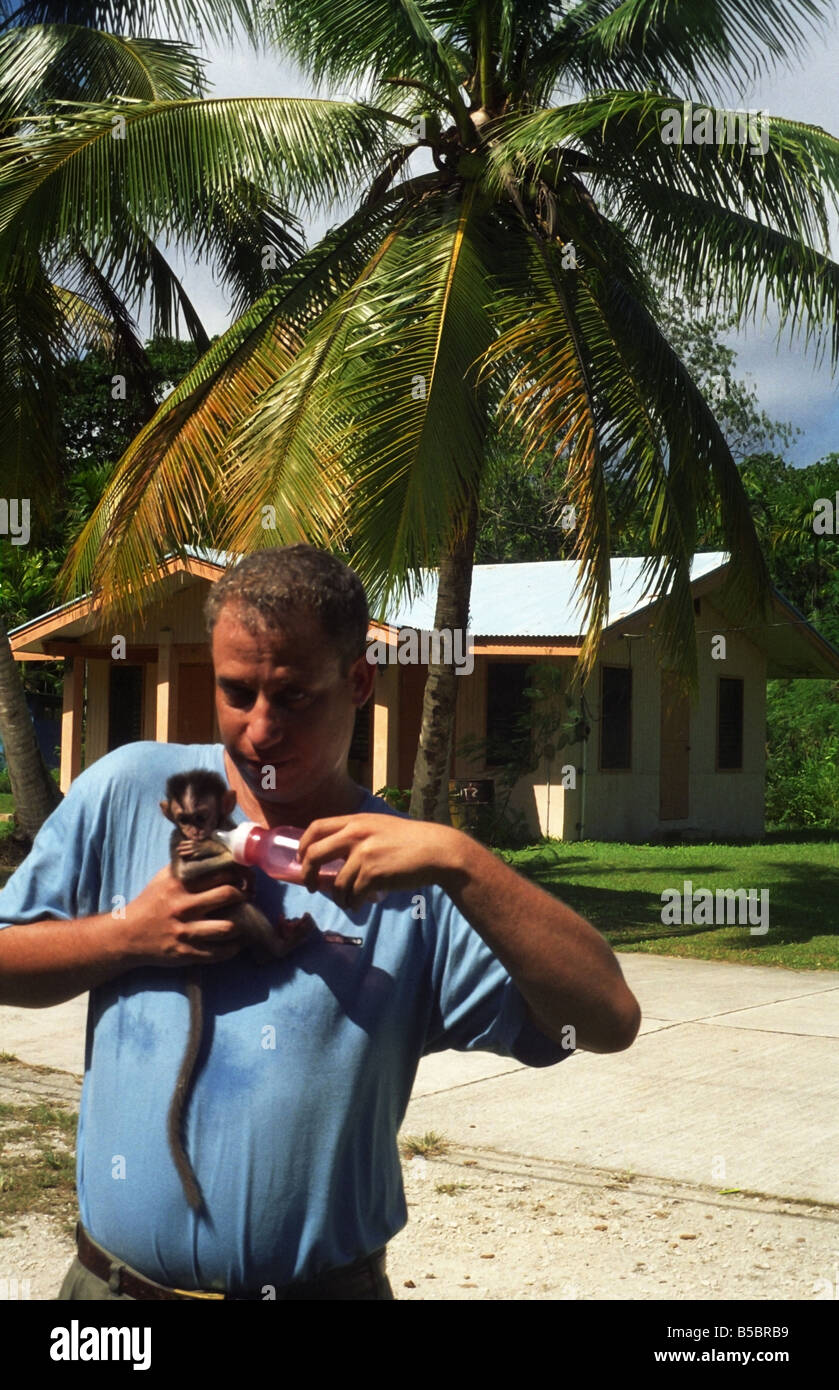 A foreigner plays with a baby monkey in the tropical island of Anguar ...