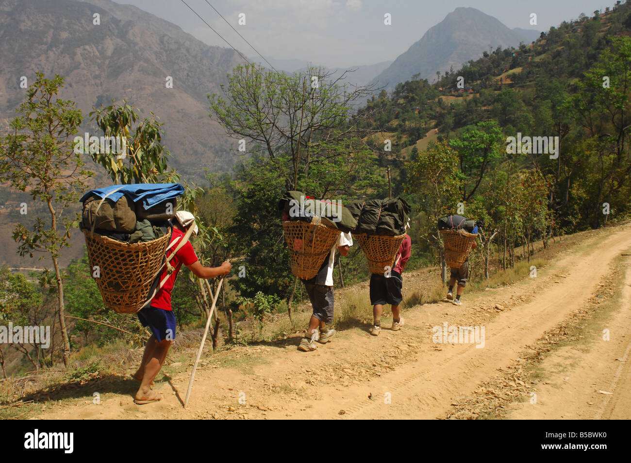 Nepali porters trekking through the hills of western Nepal Stock Photo ...