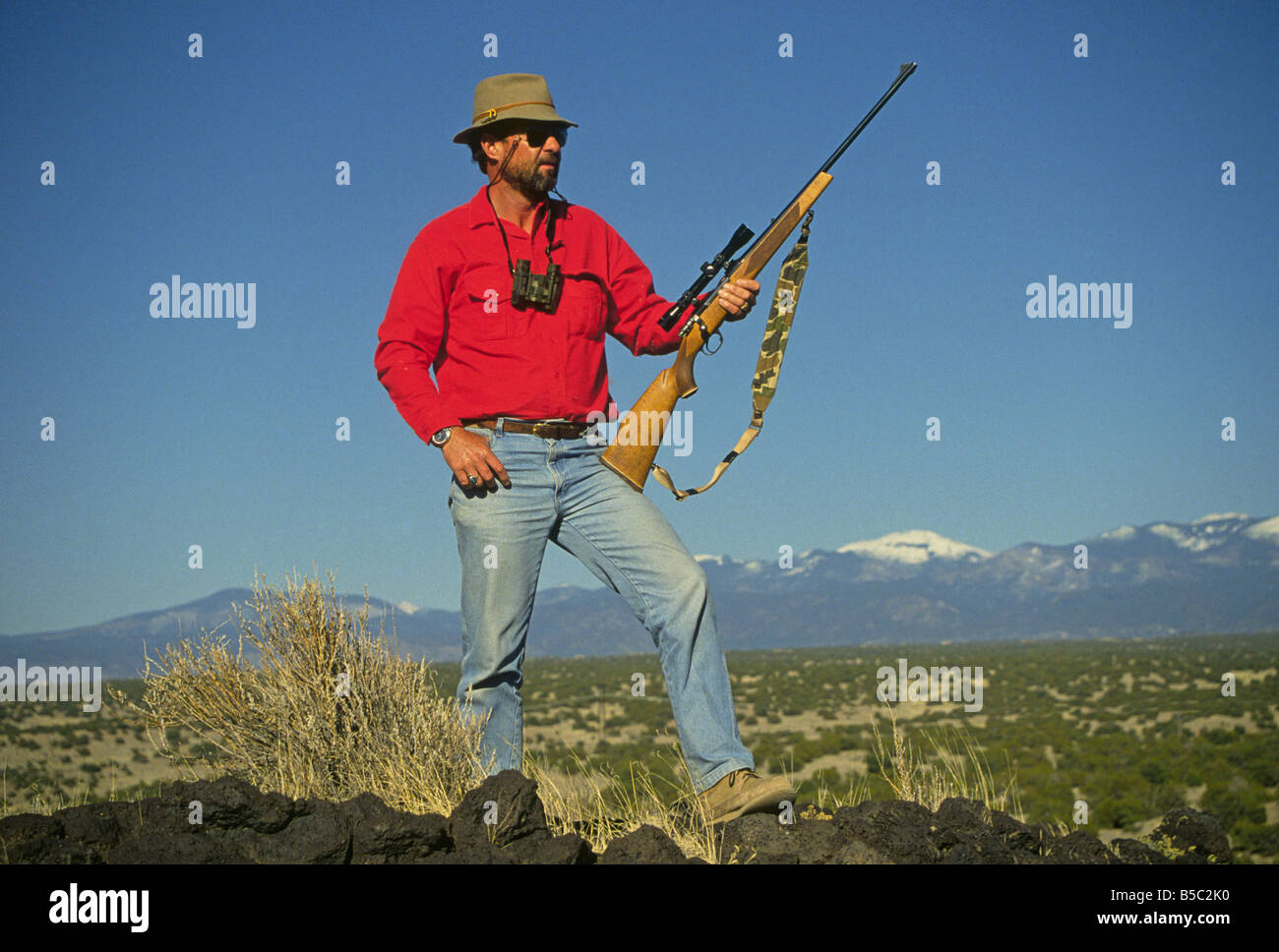 A deer hunter with a high powered caliber 270 rifle scans the high ...