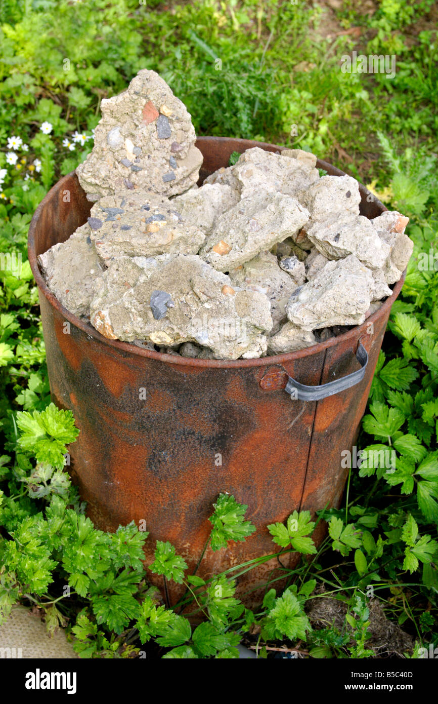 Rusty bin containing concrete rubble in garden Stock Photo - Alamy