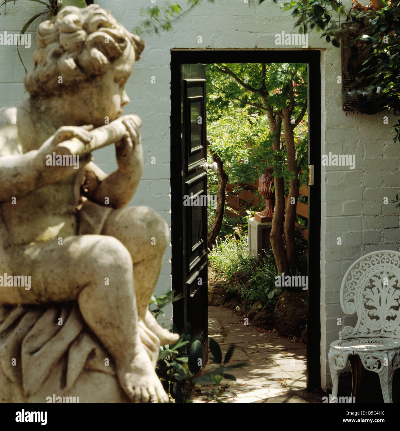 Classical statue of flute-playing cherub in courtyard with view of ...