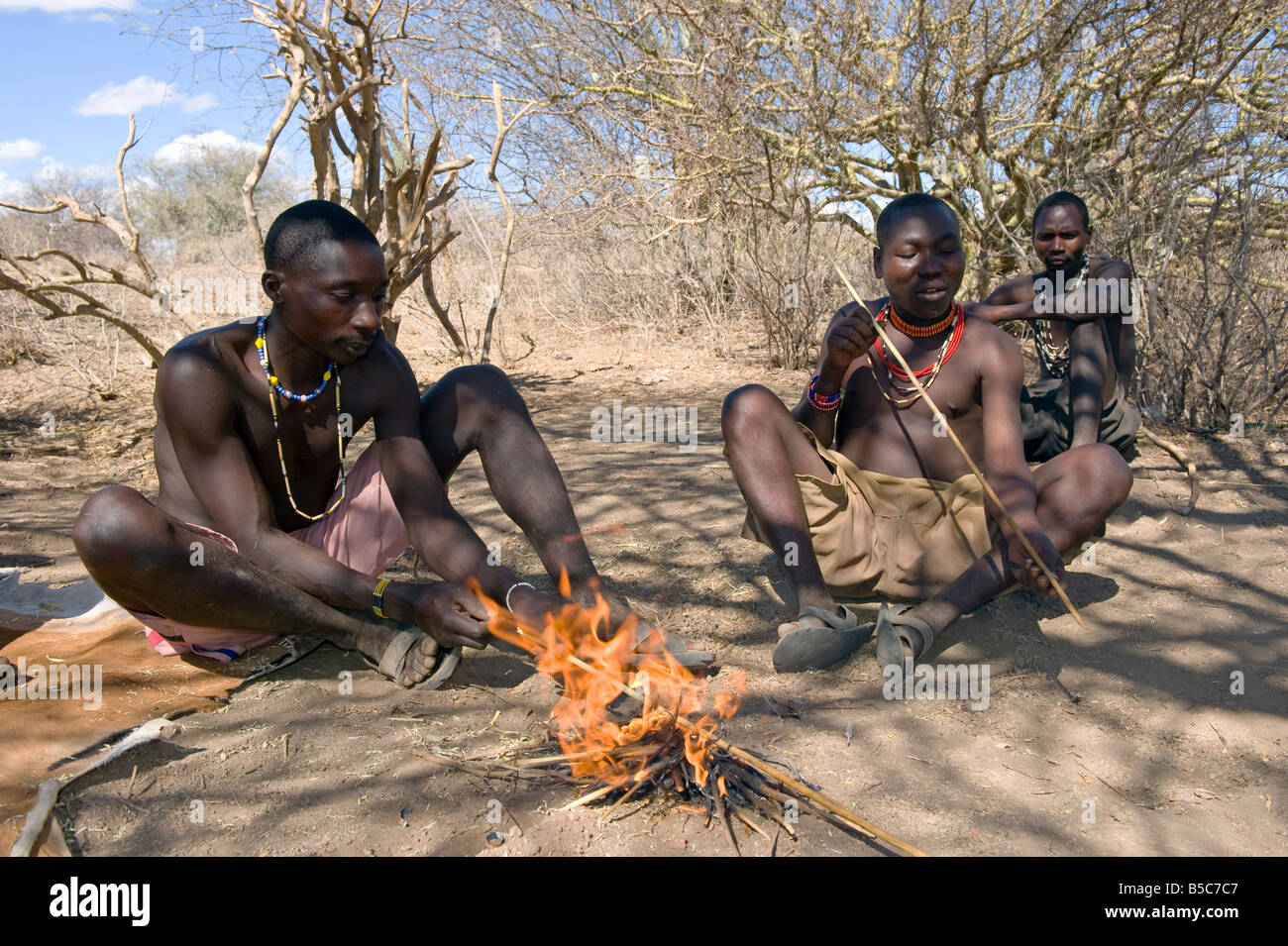 Hadza men bending a hunting arrow over a fire Lake Eyasi Tanzania Stock ...