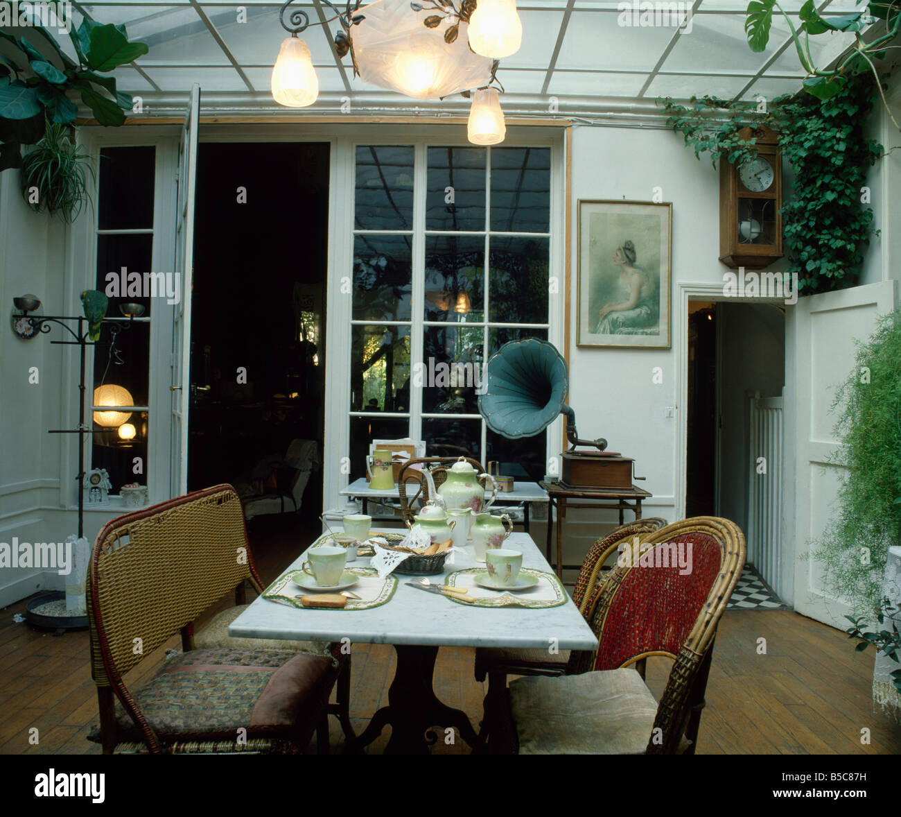 Edwardian glass light above coffeepot and cups on table with rattan ...