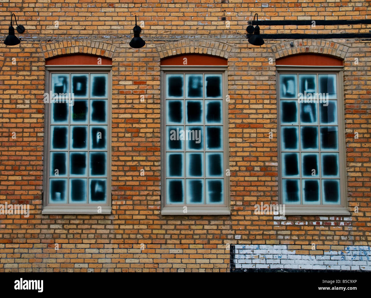Frosted windows in a brick wall with lights on wall Stock Photo - Alamy
