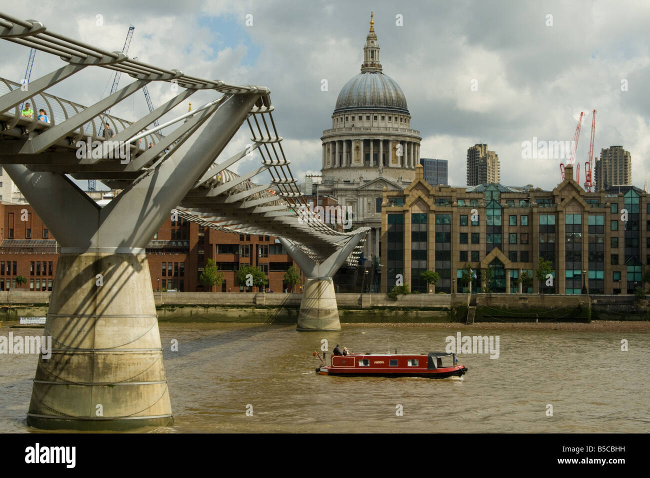 A canal barge passing under the Millenium Bridge with St Pauls ...