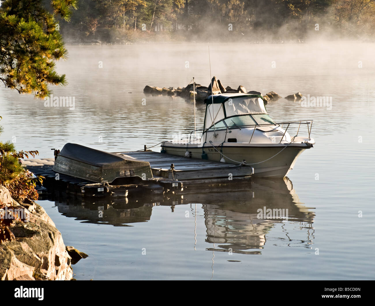A boat moored at a dock covered in frost with a mist rising off the ...