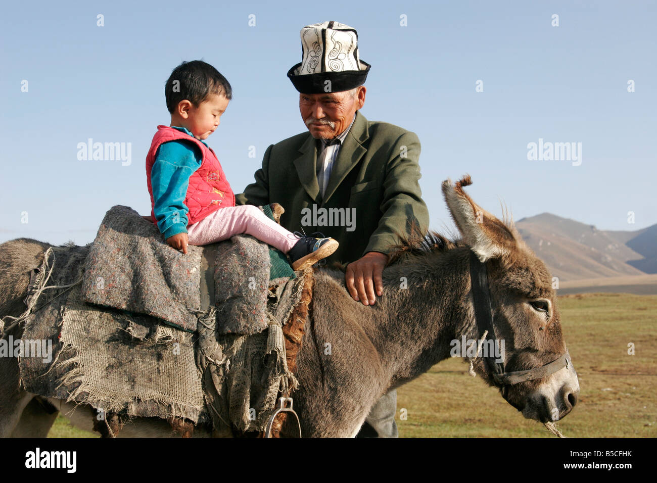Old Kyrgyz man wearing traditional kalpak (hat) and boy sitting on ...