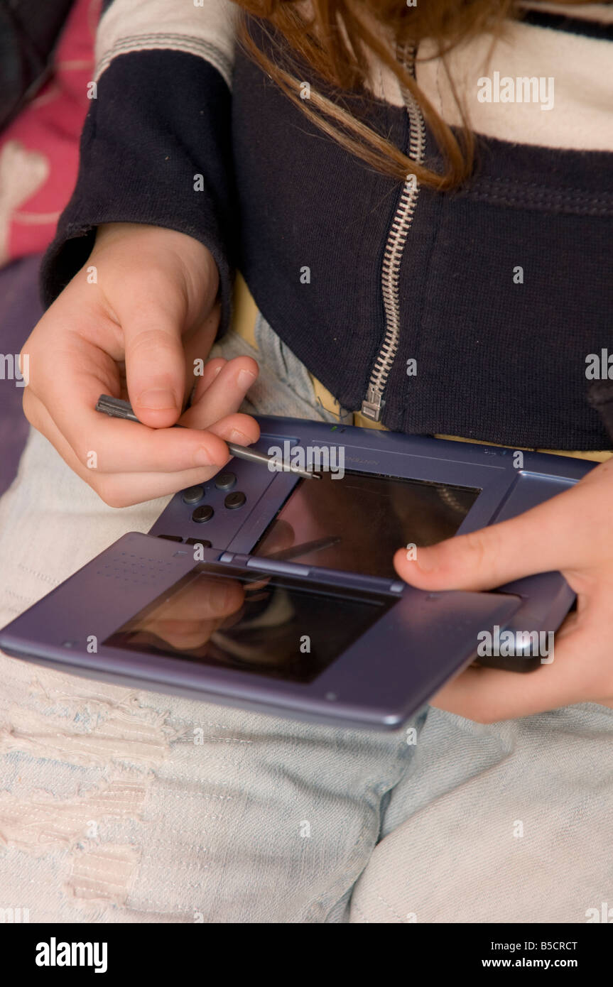 Teenage girl sitting on sofa playing computer games on Nintendo DS ...