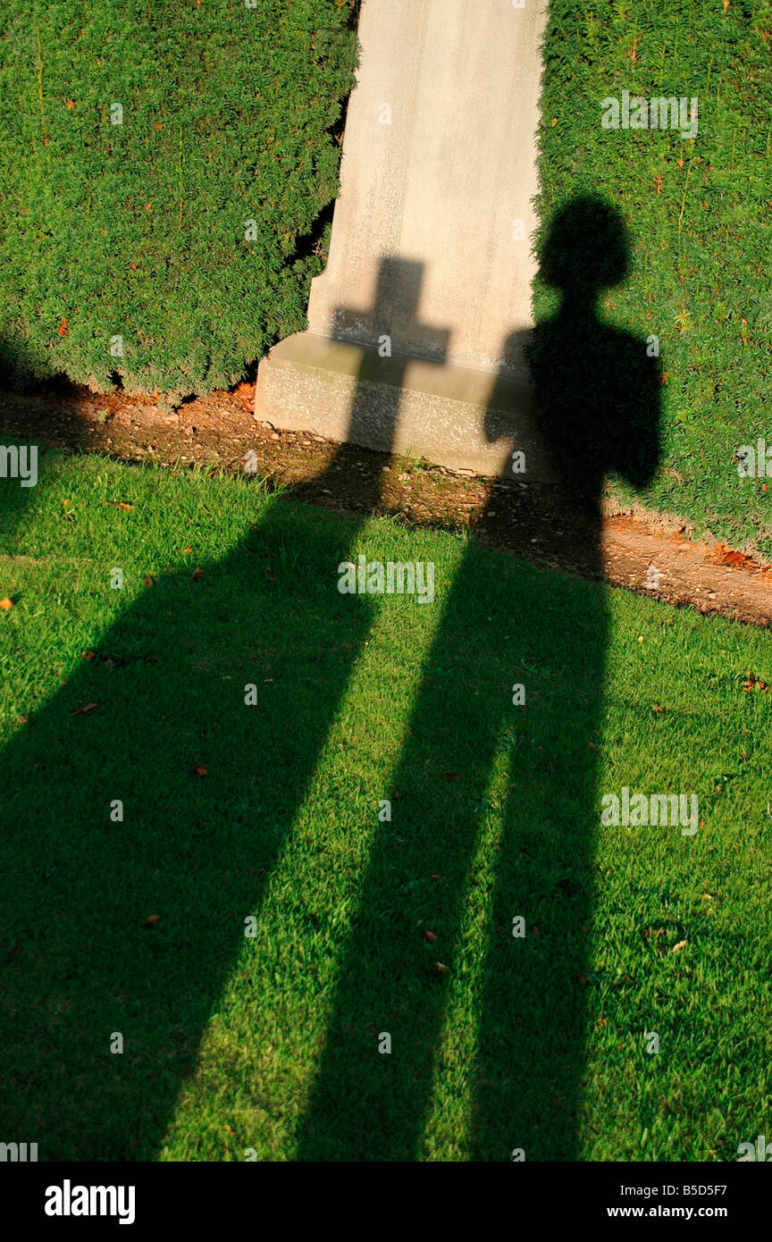 Shadow of a gravestone cross and standing person on the base of another ...