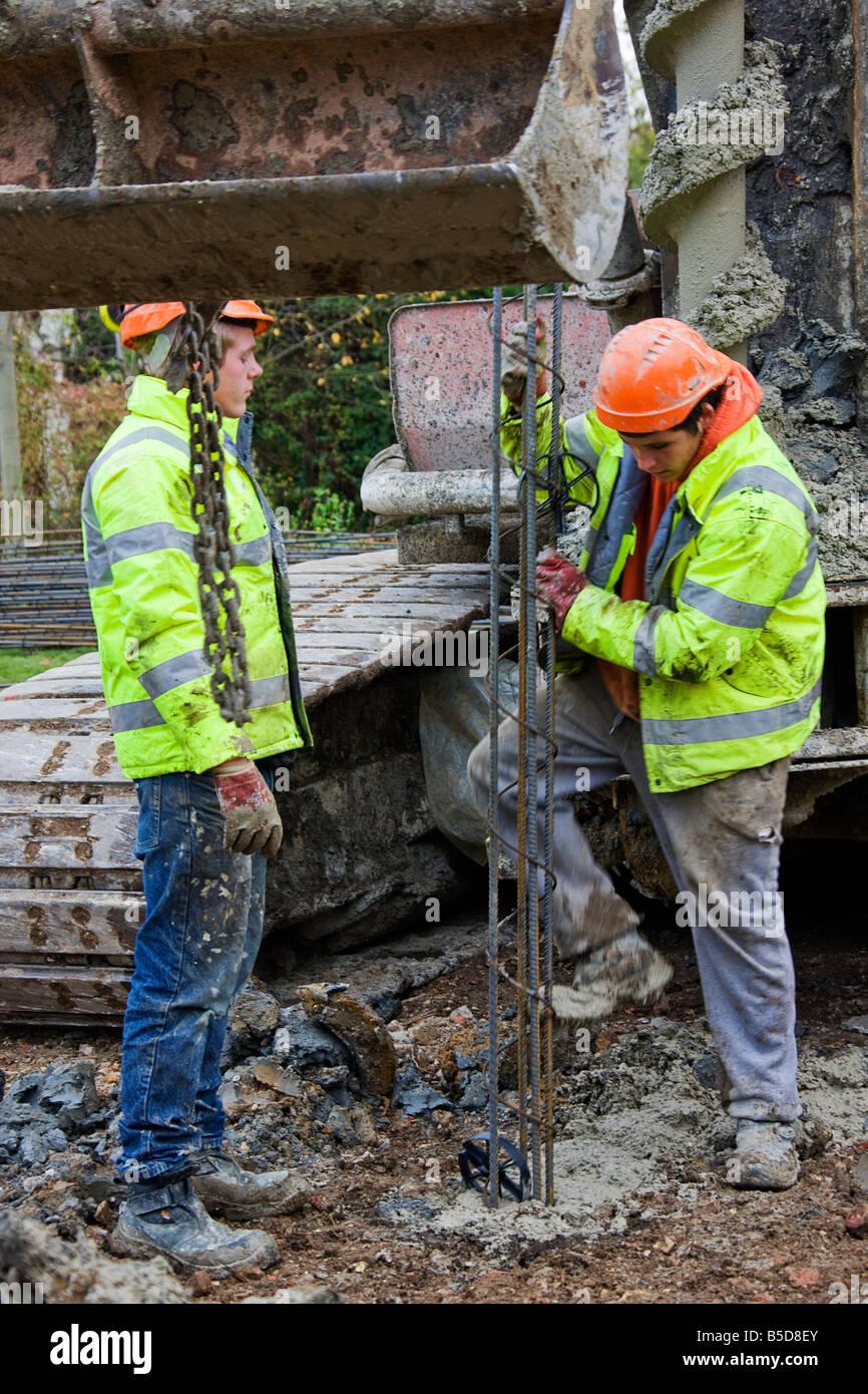 Workmen working the steel reinforcement bars down into concrete piles ...