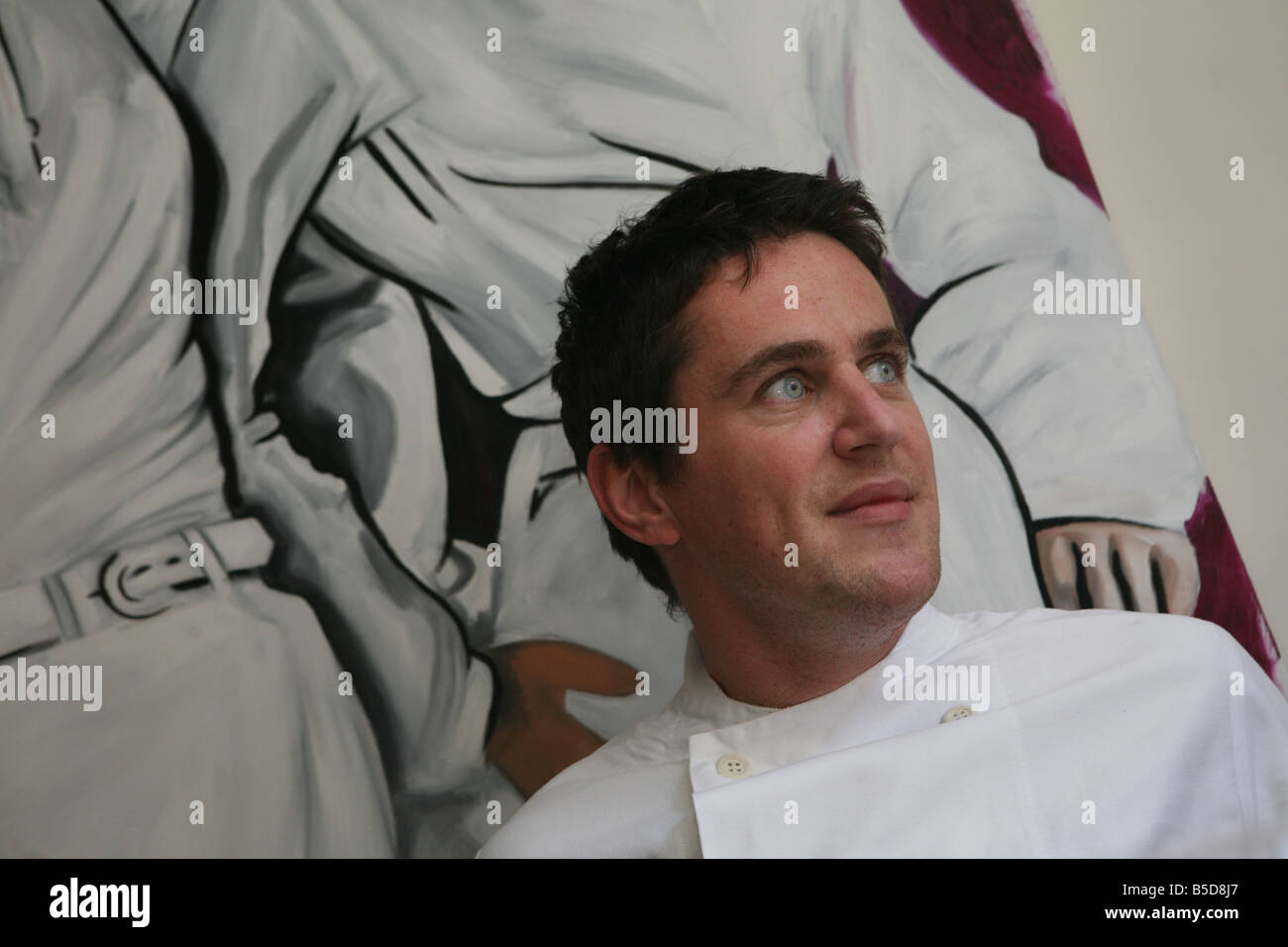 a portrait of a handsome chef in his chef whites sitting on a table in ...