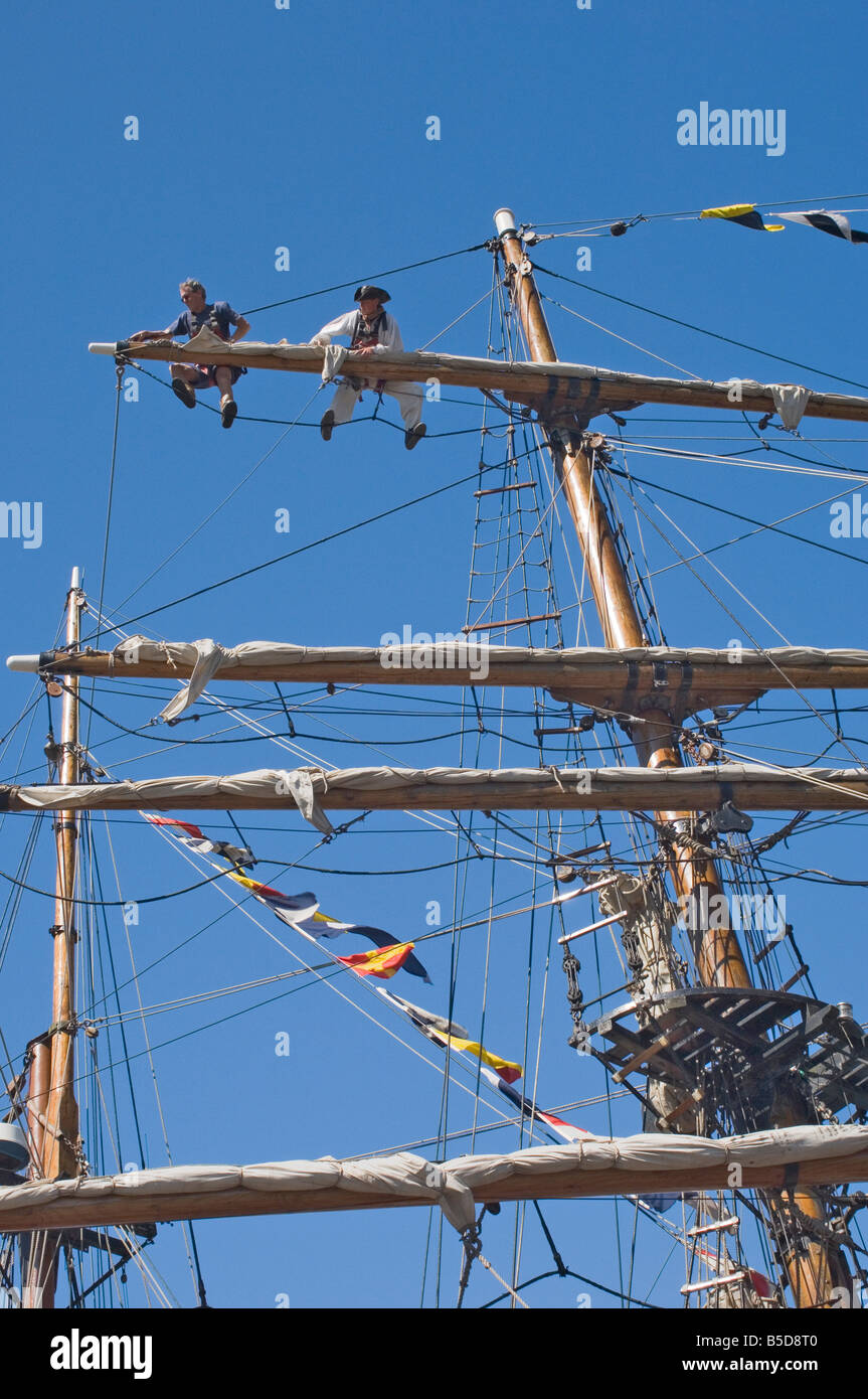 Detail of main mast of tall ship with two seamen on top yard securing ...