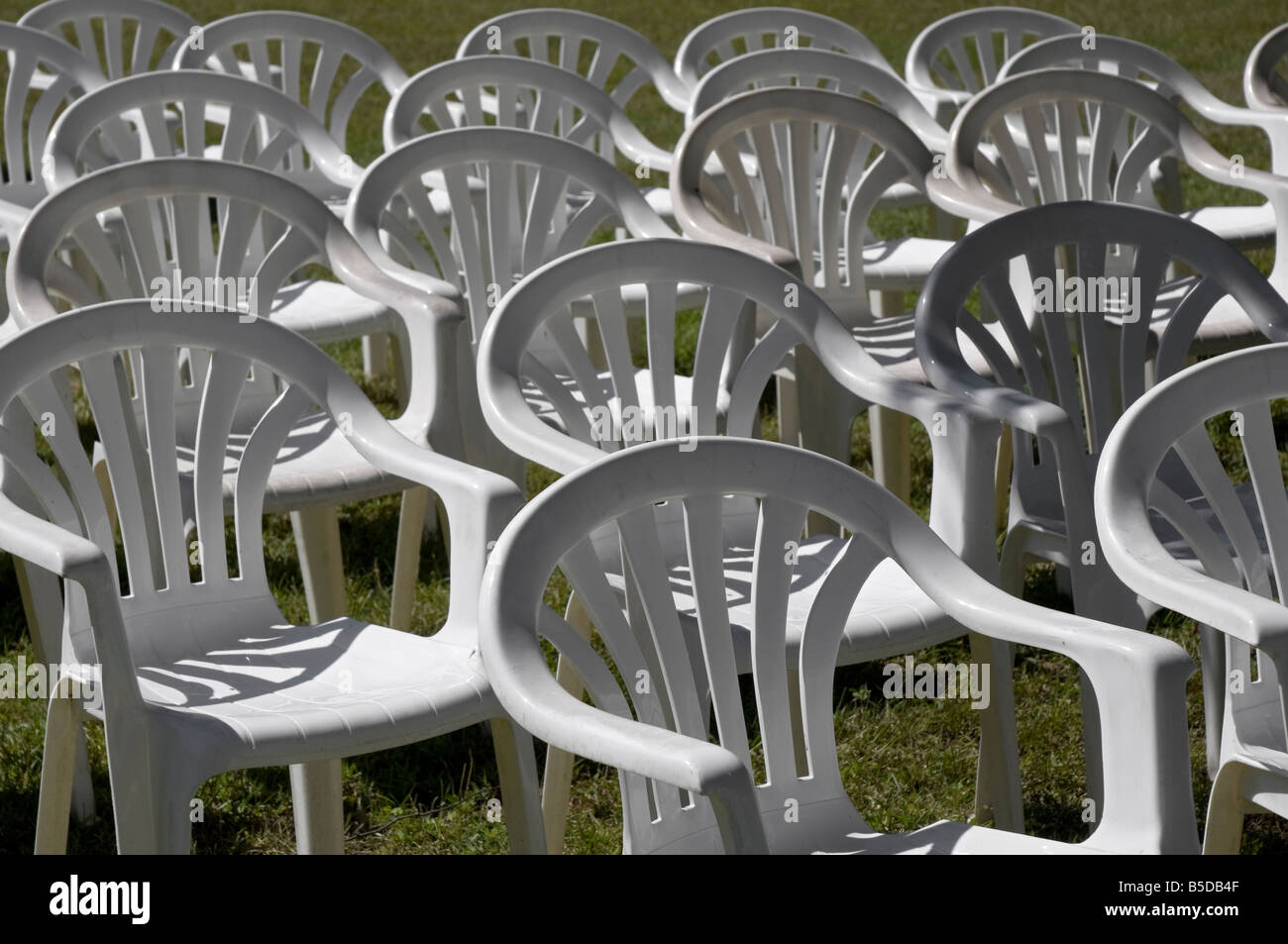 line up of white chairs in garden setting Stock Photo - Alamy