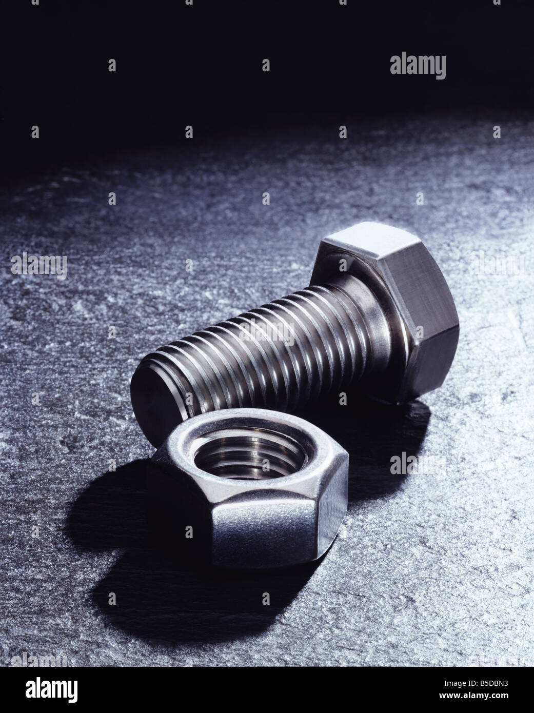 Nut and bolt on slate with dramatic back lighting Stock Photo - Alamy