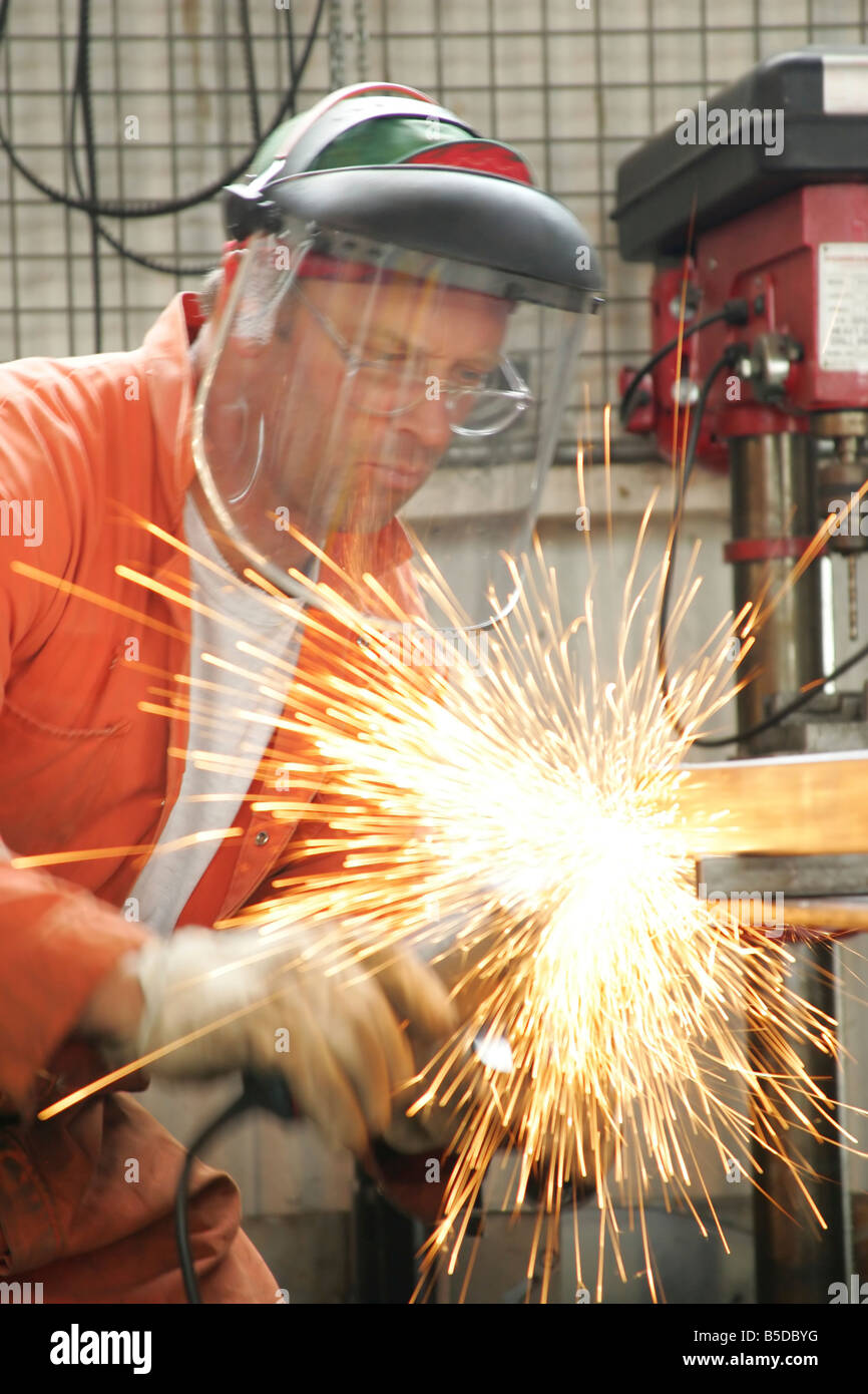 A warehouse worker grinding a corner of a weld with sparks flying Stock ...