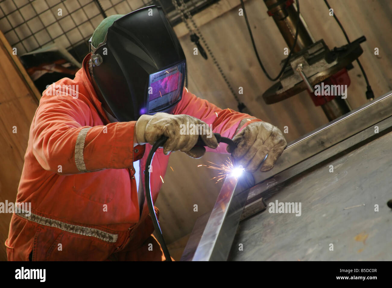 A warehouse worker applying a tig weld with sparks flying Stock Photo ...