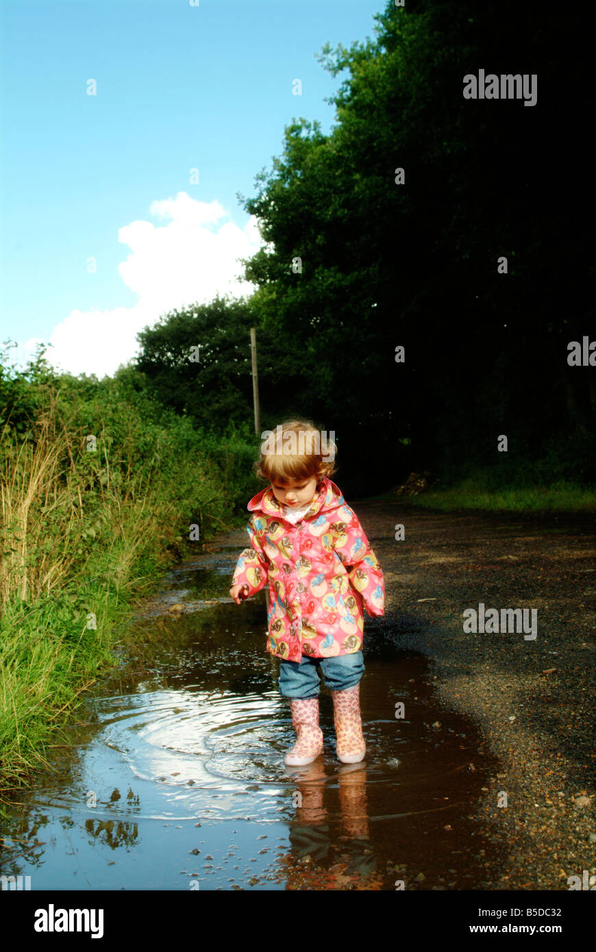 Little girl wading through a huge puddle in the countryside Stock Photo ...