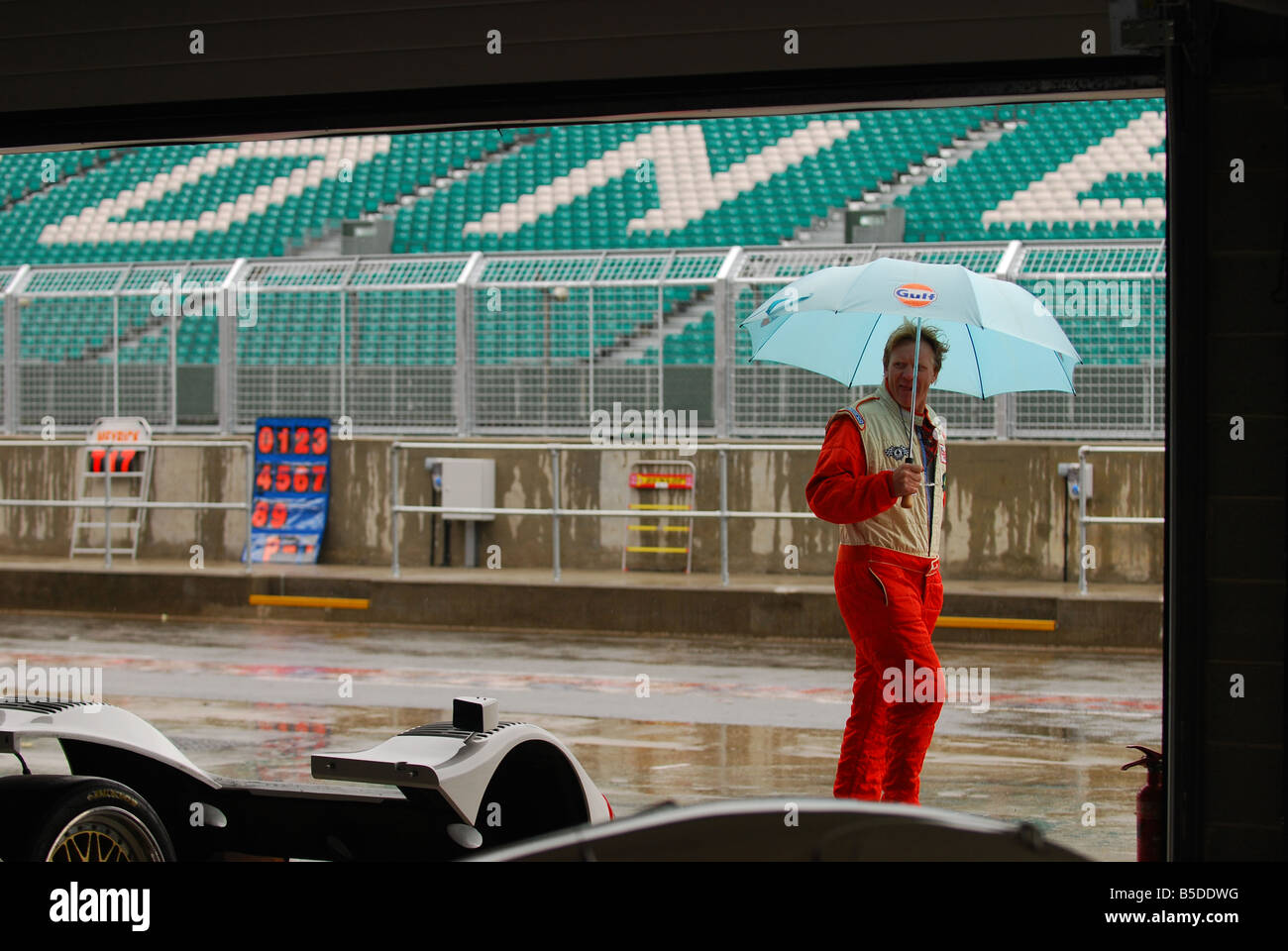 A racing driver walking past a pit garage Stock Photo - Alamy