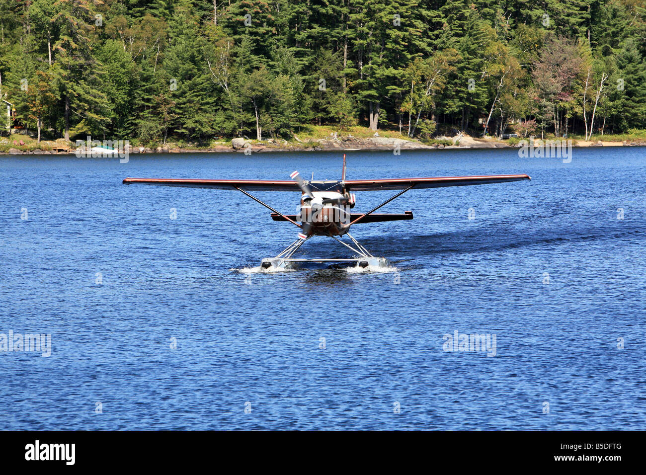 A single engine float plane taxing to the dock on Long Lake New York ...